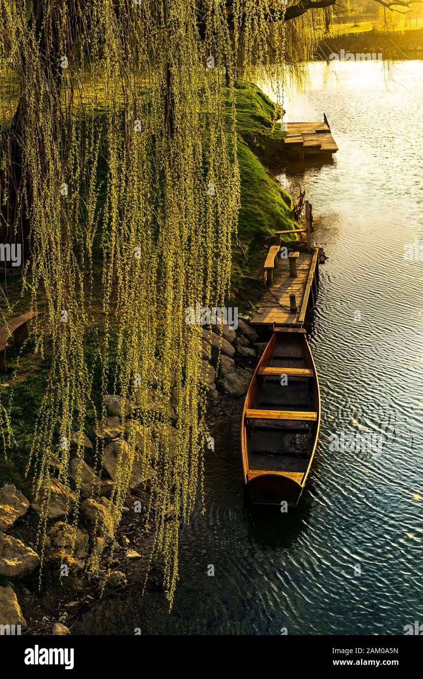 Small wooden boat floating on water in sunset time Stock Photo - Alamy