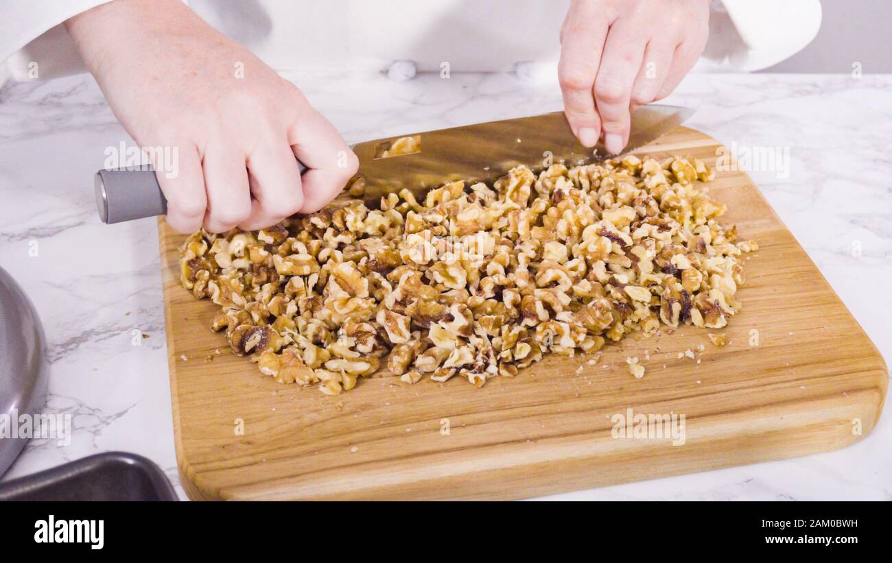 Step by step. Chopping walnuts with kitchen knife on a wood cutting ...