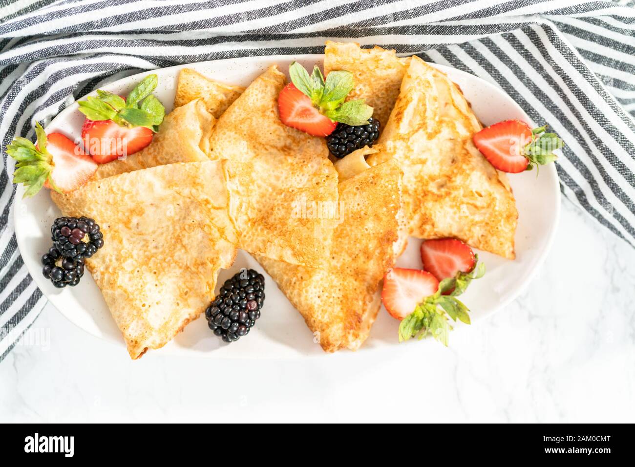 Flat lay. Freshly baked crepes folded in triangles and garnished with ...