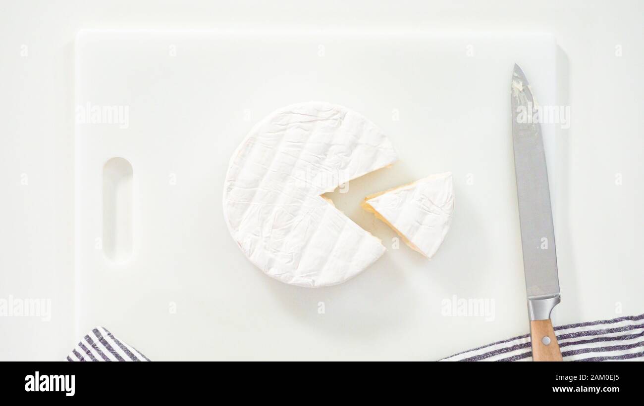 Flat lay. Slicing a large slice of gourmet cheese on a white background ...