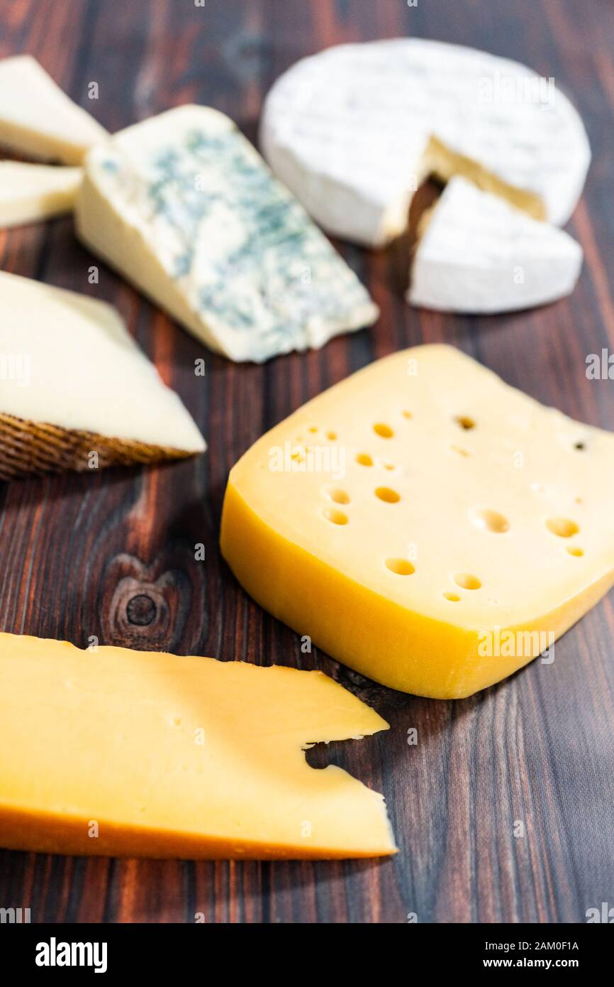 Variety of large gourmet cheese wedges on a dark wooden background ...