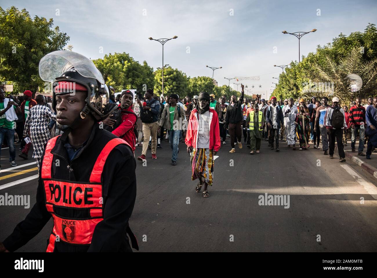 Dakar, Senegal. 10th Jan, 2020. A crowd march behind a policeman in ...