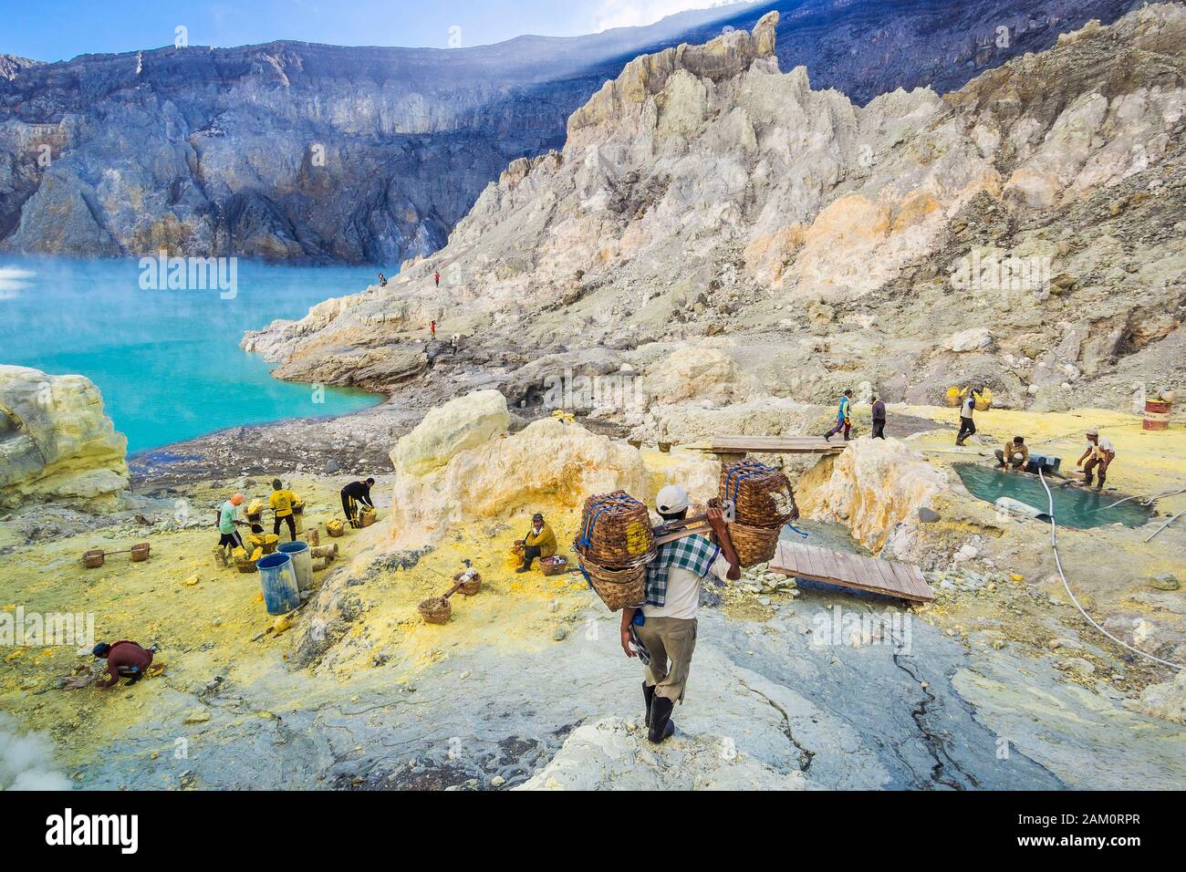 Sulphur miner hiking down into the crater of Kawah Ijen volcano in East ...