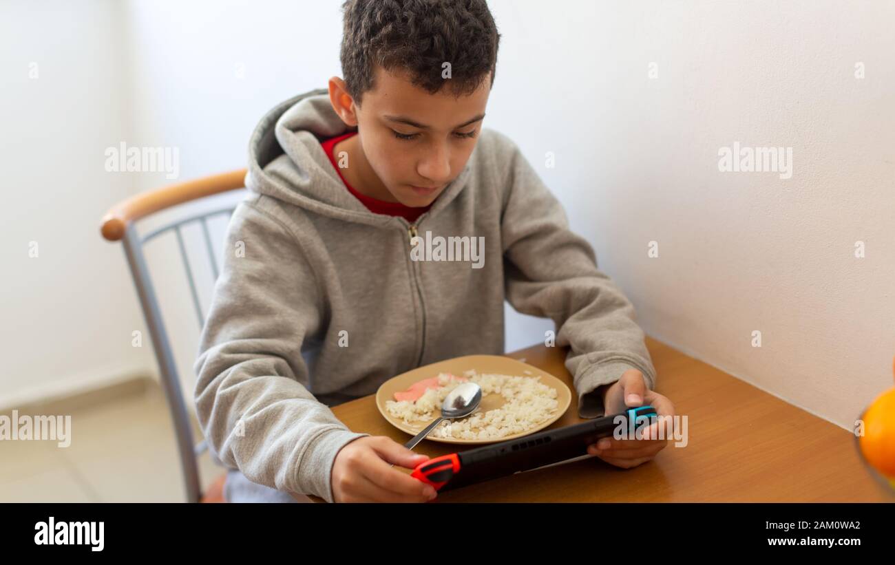 Kid eating rice and surfing on internet or playing video games on ...