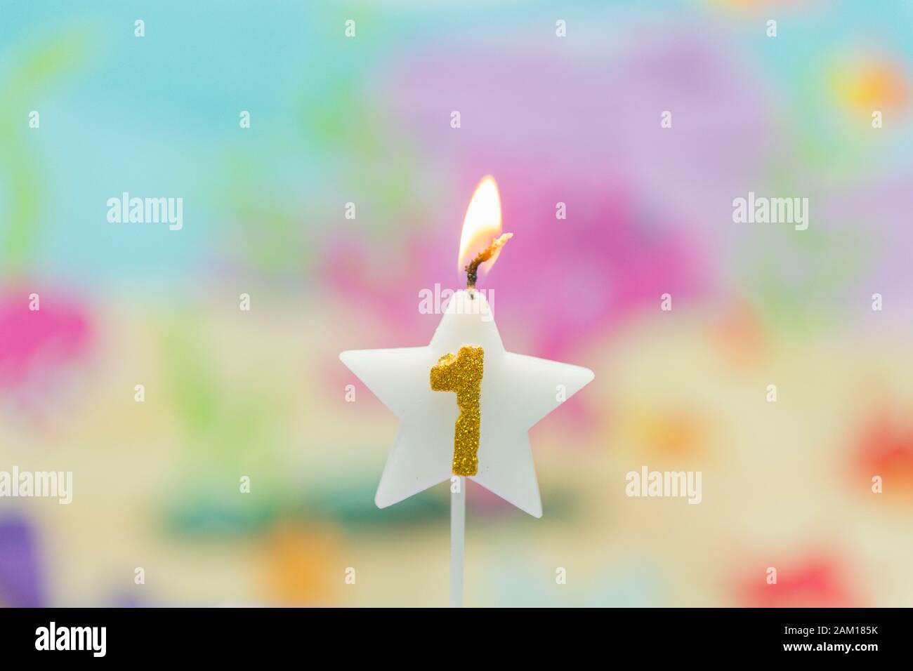 Lighted birthday candle in star shape with blurred background. 1 year ...