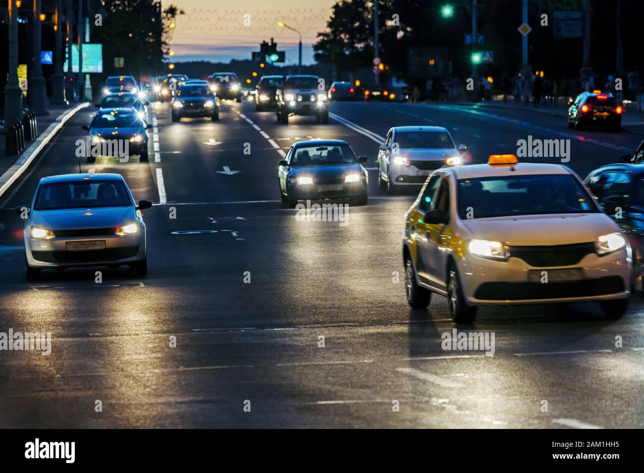 city road at night. cars driving in the street with the turned on ...