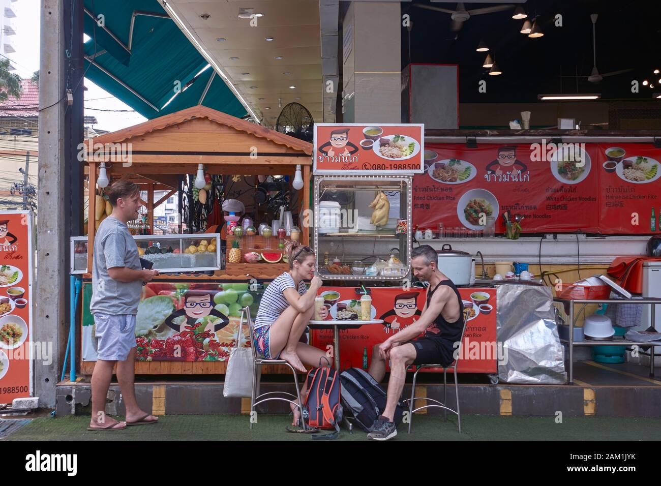People eating outside on the pavement at a street snack bar Thailand ...