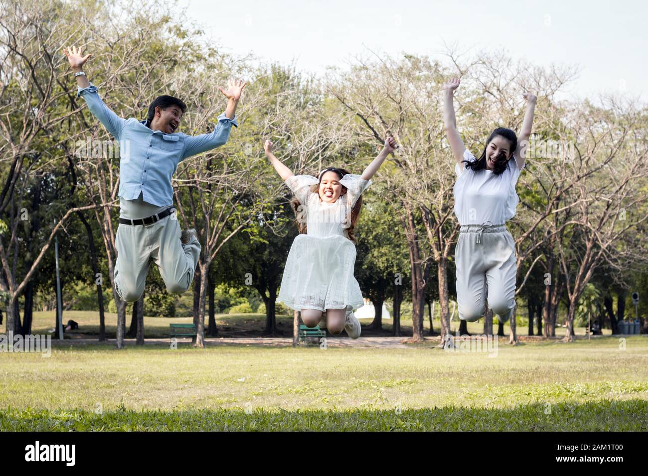 Parents and children jump happy in the park. Asian family jumping in ...