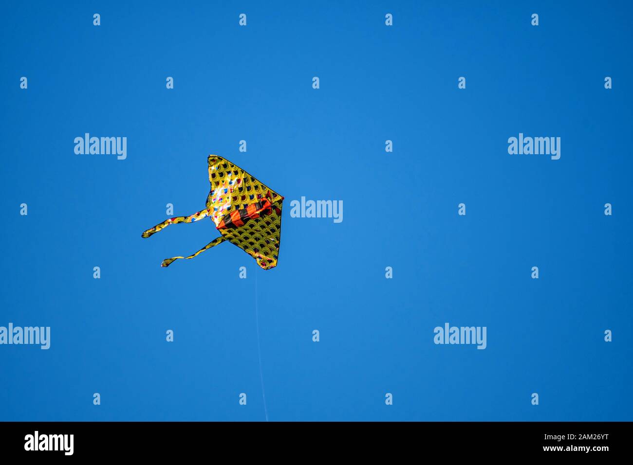 Colorful yellow kite flying on the blue sky Stock Photo - Alamy