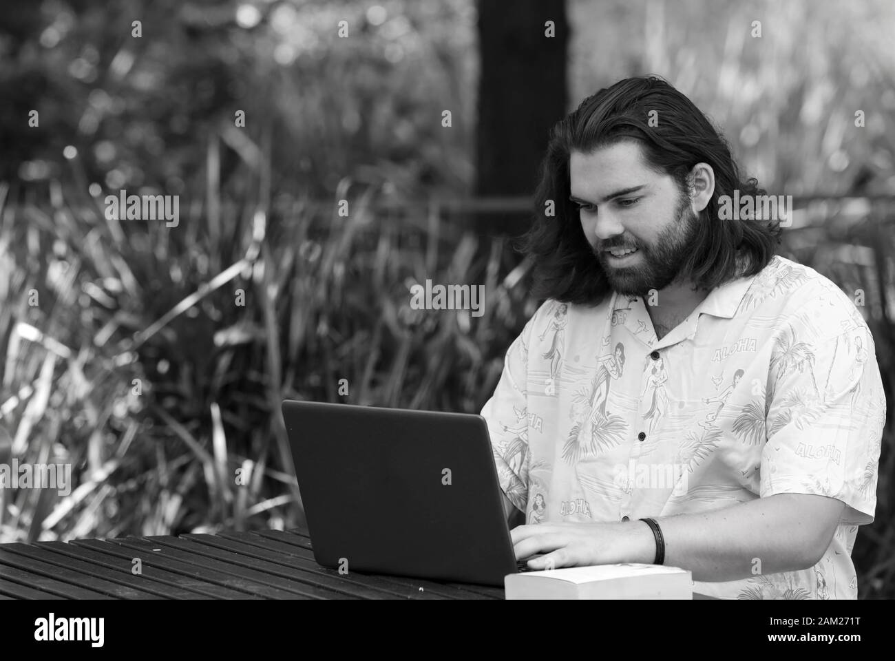 A black and white image of a young man on his laptop computer studying ...