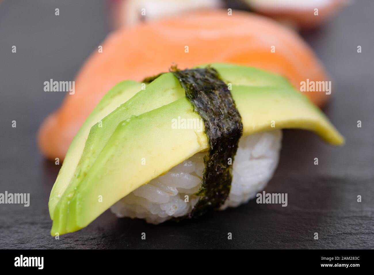 detail of an avocado nigiri on a slate plate, fruit rolled with nori ...