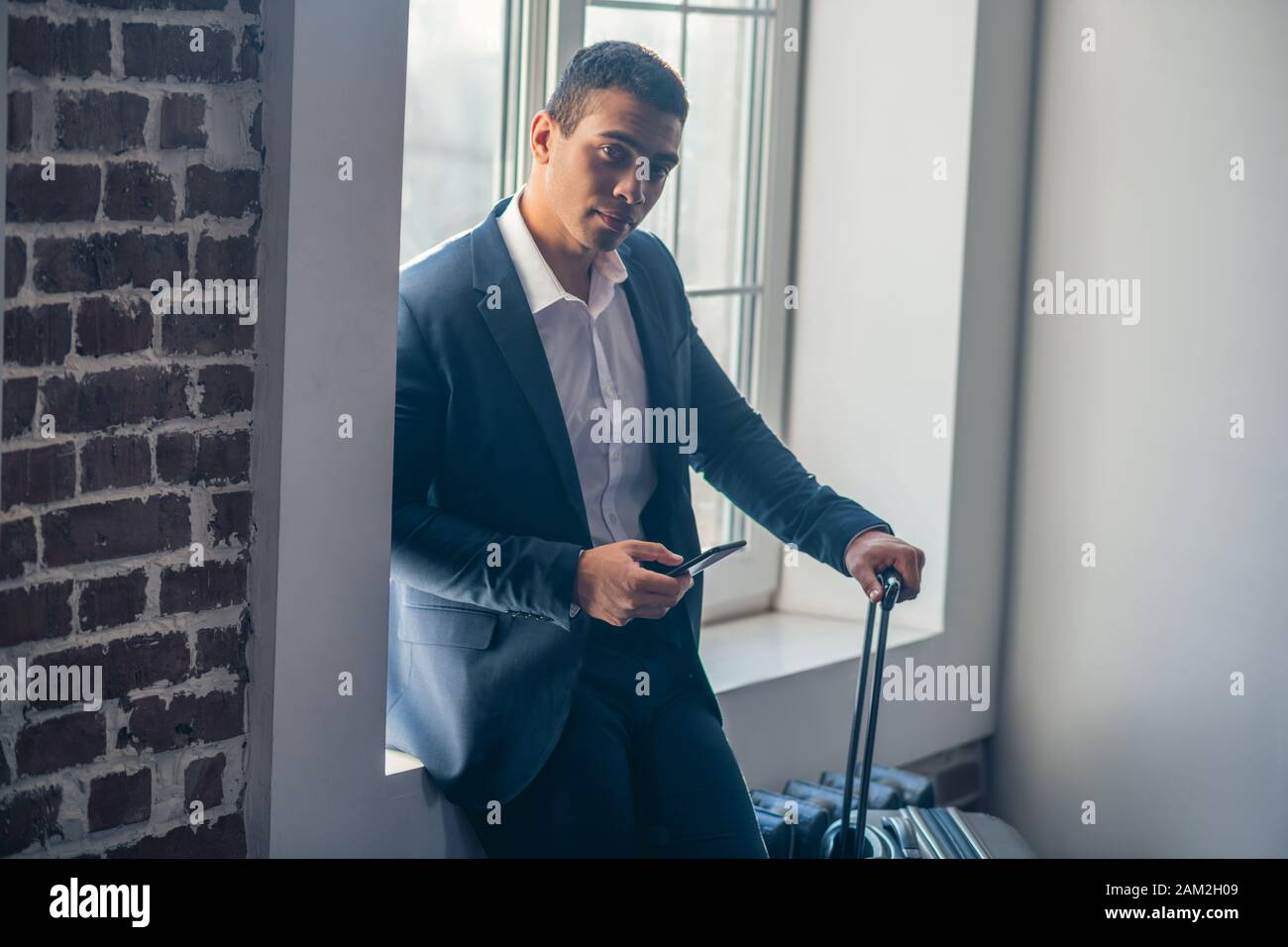 Dark-haired young man in elegant suit waiting near the window Stock ...