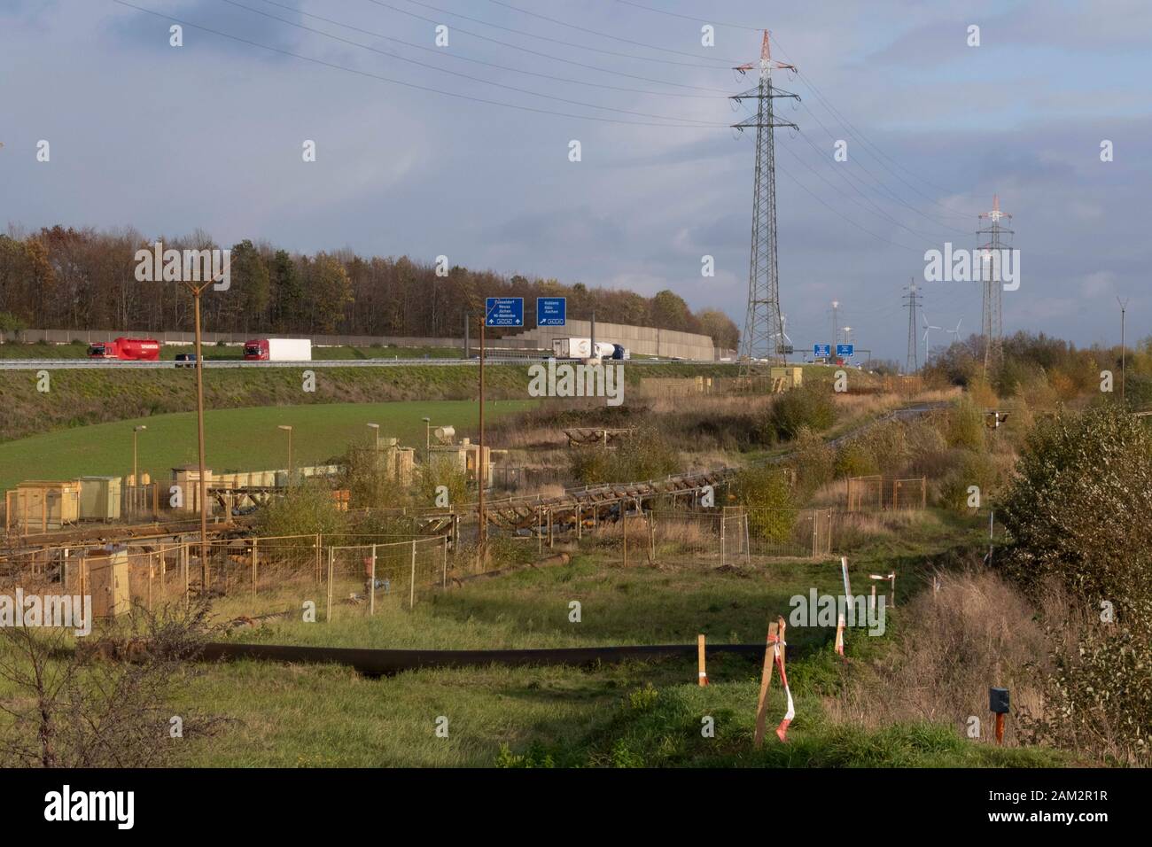 Electricity pylon by rail tracks and motorway near open pit coal mine ...