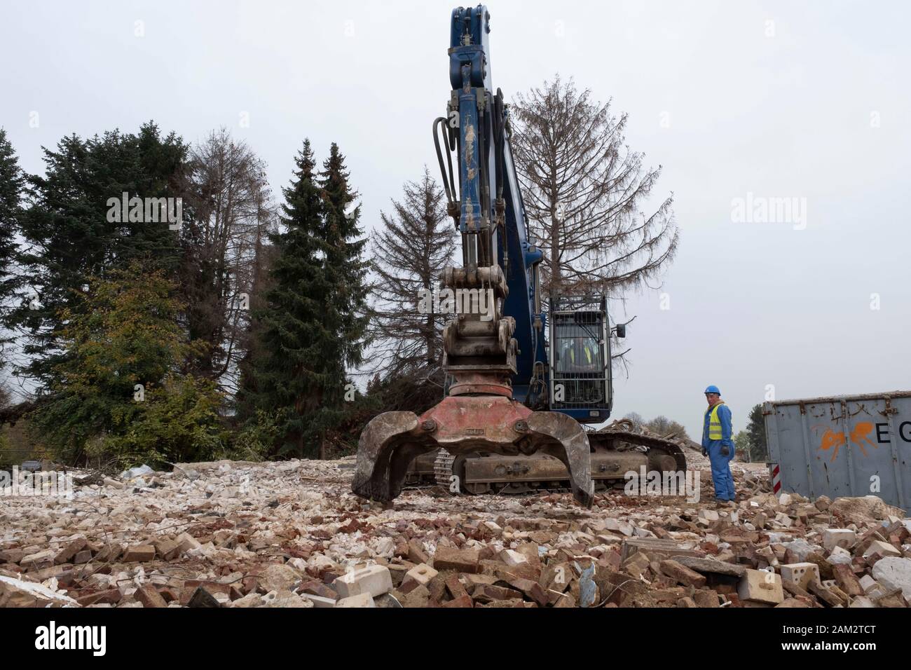 Workmen using hydraulic grab machine on demolition site in abandoned ...