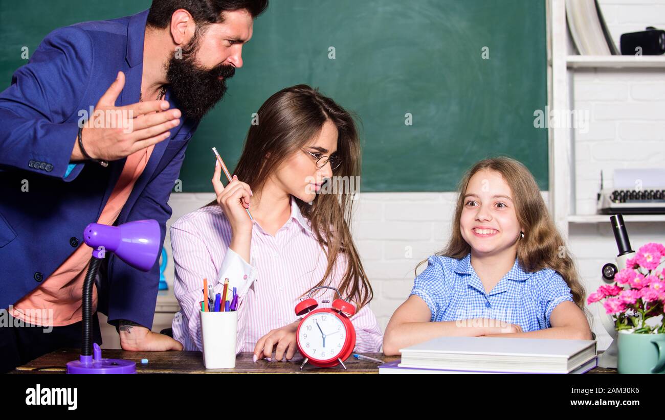 Overprotective parenting style. Little girl doing homework. Dad mom ...