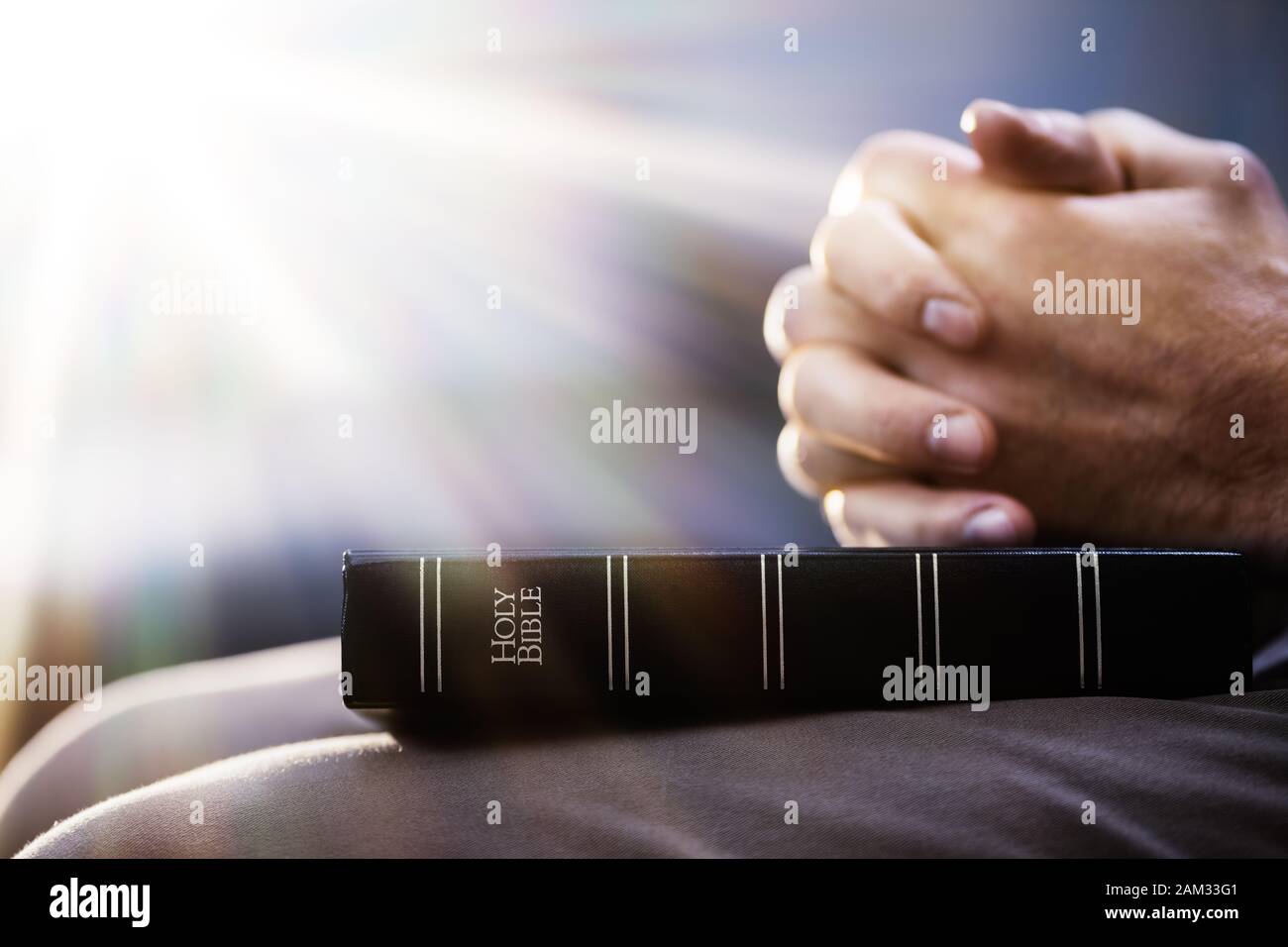 Sunlight Falling On Hand Over Bible While Praying Stock Photo - Alamy