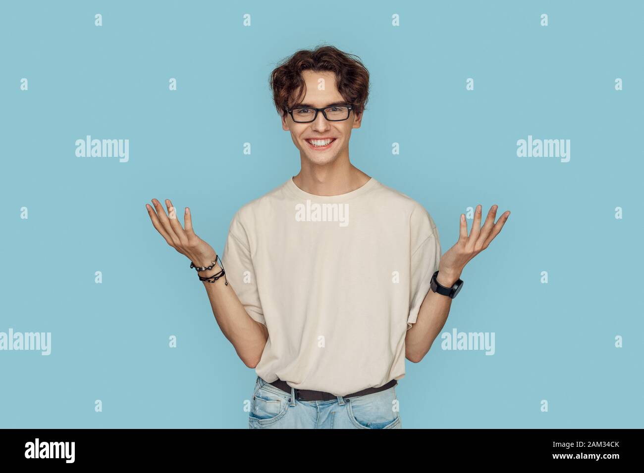 Freestyle. Man in glasses standing isolated on gray hands aside smiling ...