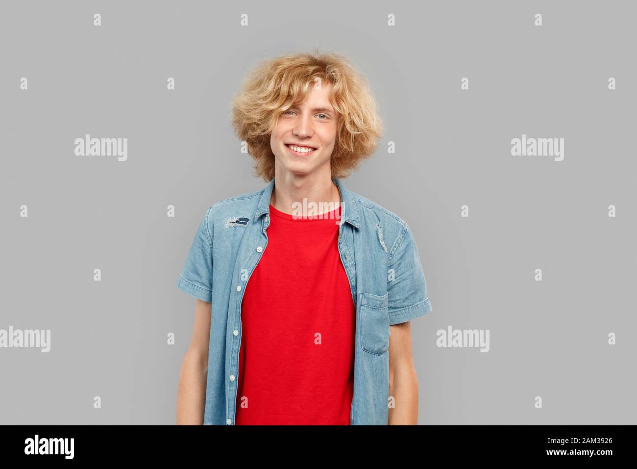 Young adult guy standing on grey background Stock Photo - Alamy