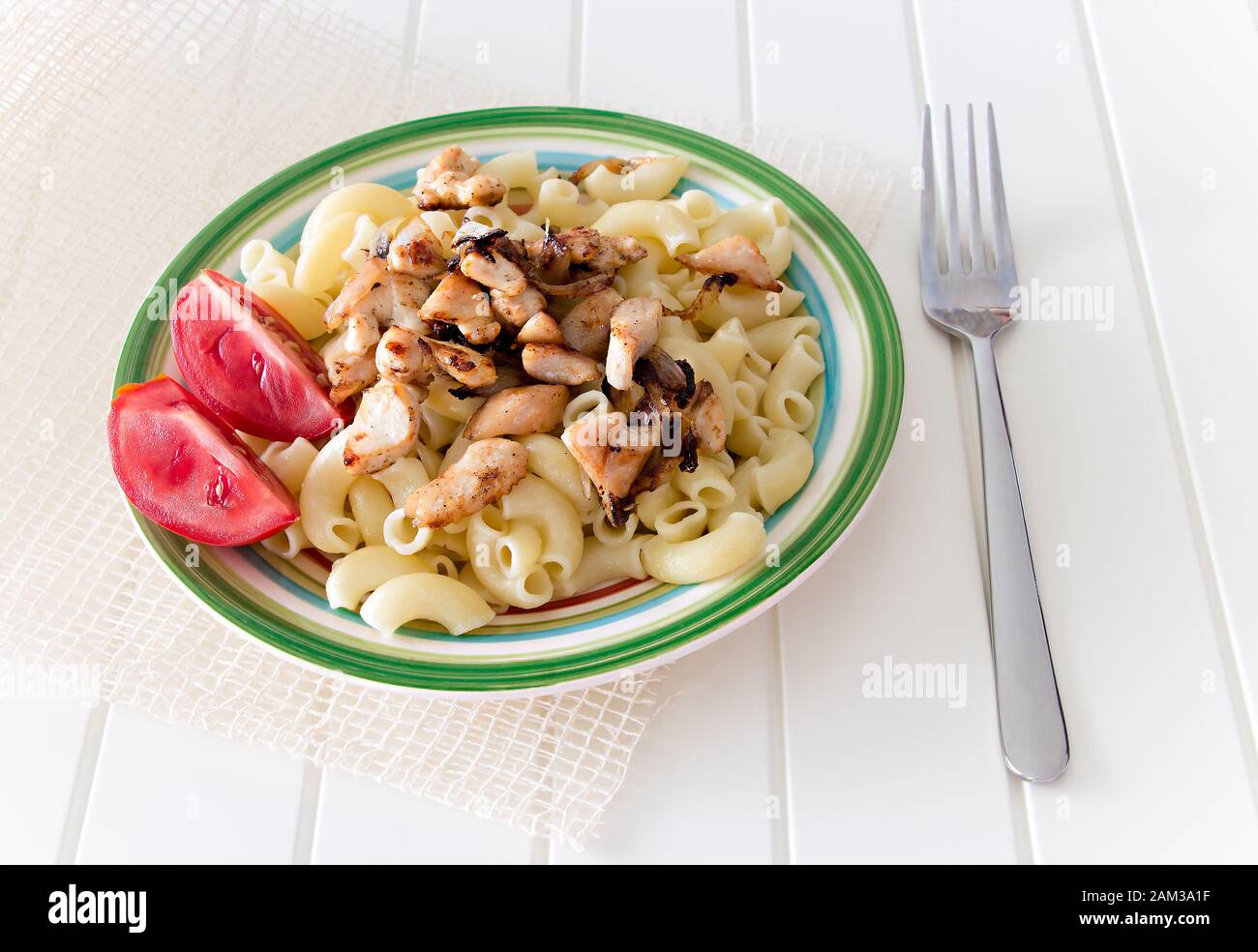 Gomiti Pasta with fried chicken and onion pieces with tomato and fork ...