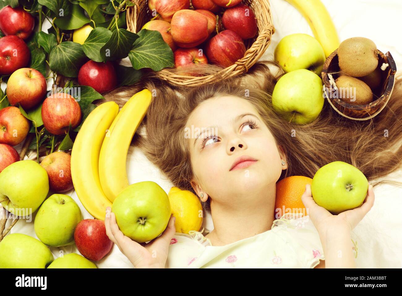 little happy girl or cute hungry child eating colorful fruit of apple ...