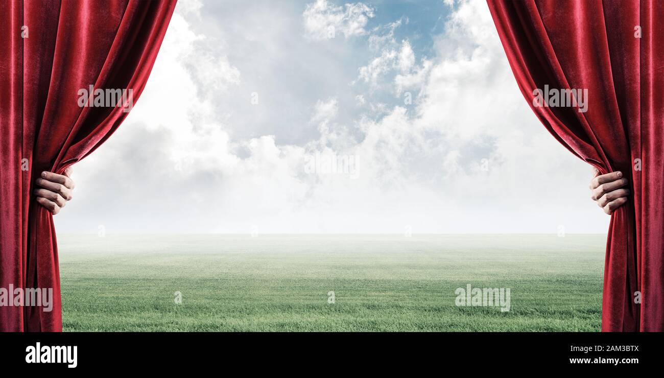 Green meadow behind red curtain and hand holding it Stock Photo - Alamy
