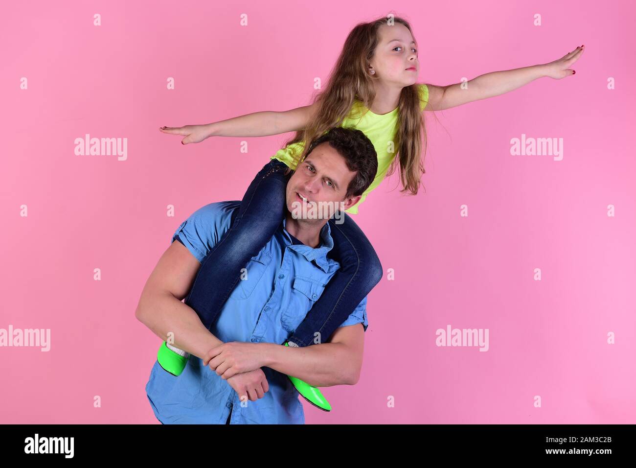 Schoolgirl puts hands wide pretending to fly. Girl and man with happy ...