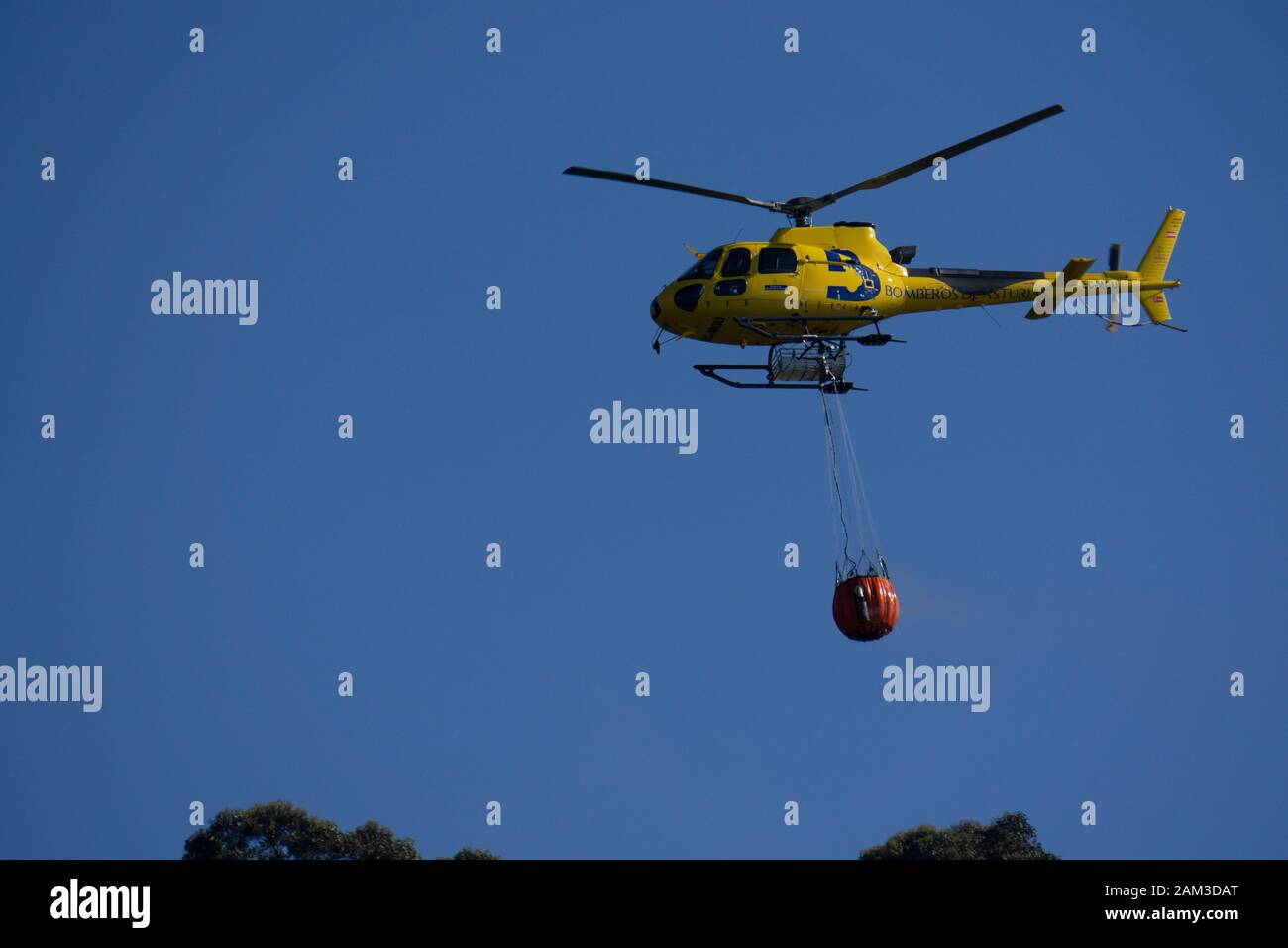 Yellow helicopter of Astoria firefighters in action with bucket ...