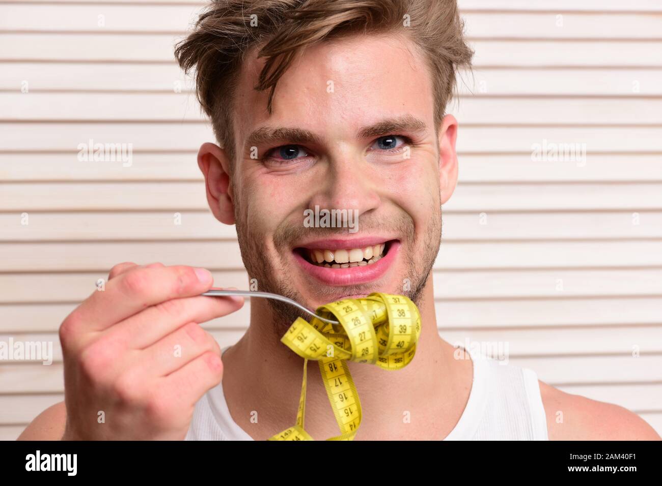 Macho with smiling face holds yellow measure tape on fork. Man pretends ...