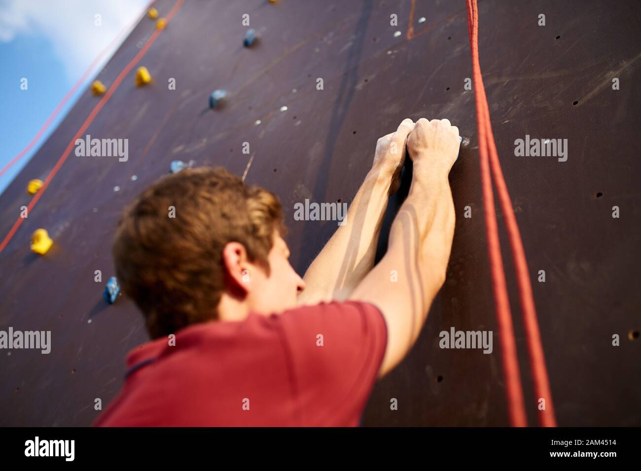Back view close-up of climber hands on a rock hook of the artificial ...