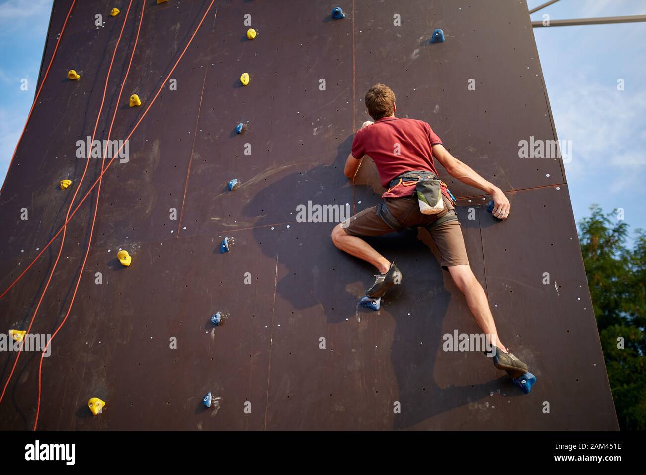 Sporty man practicing rock climbing in gym on artificial rock training ...