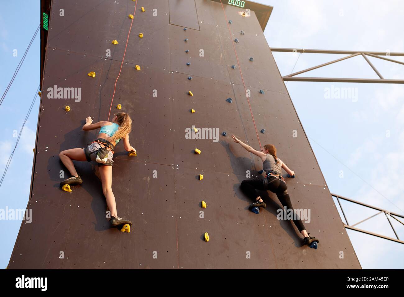 Bottom view of two young climbers approaching to finishing point on the ...