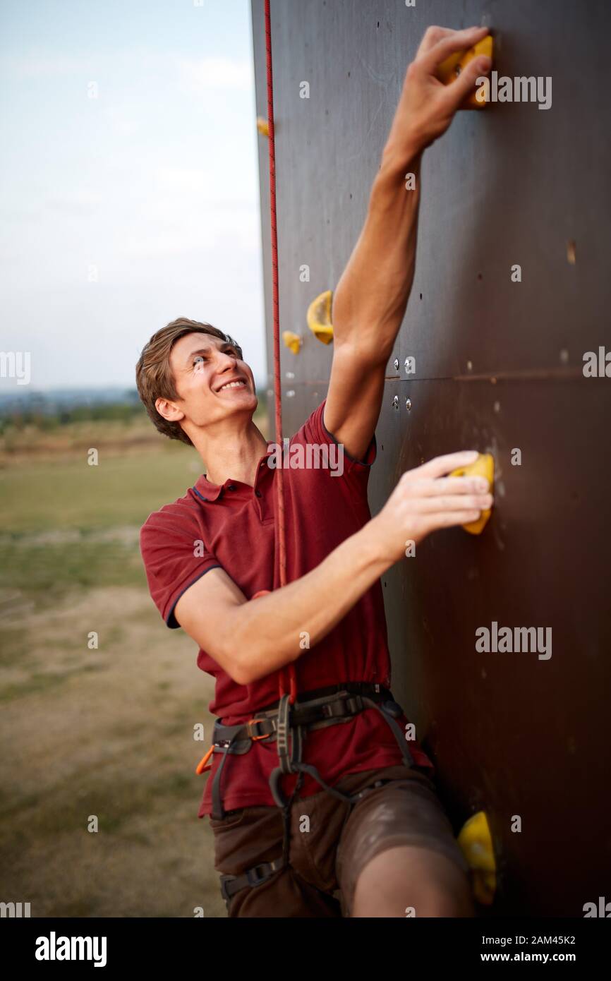 Sporty man practicing rock climbing in gym on artificial rock training ...