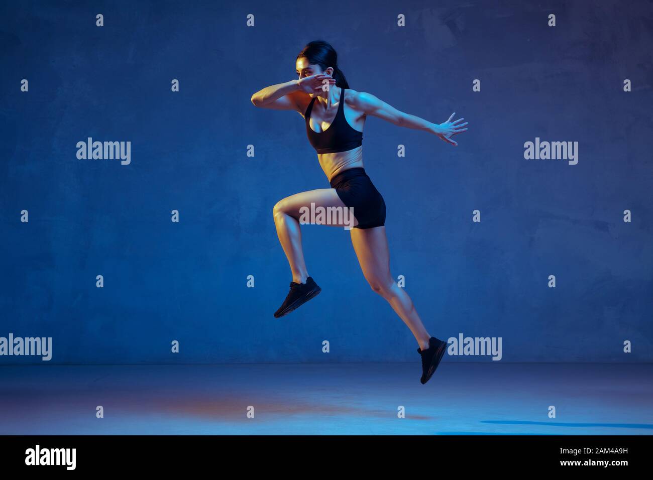 Caucasian young female athlete practicing on blue studio background in ...
