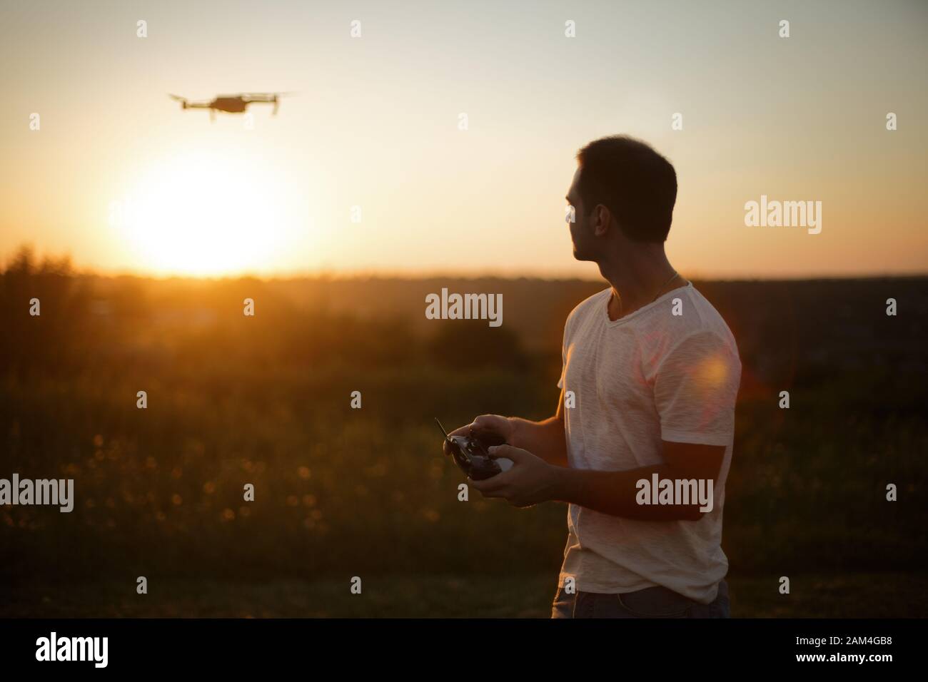 Silhouette of a man piloting drone in the air with a remote controller ...