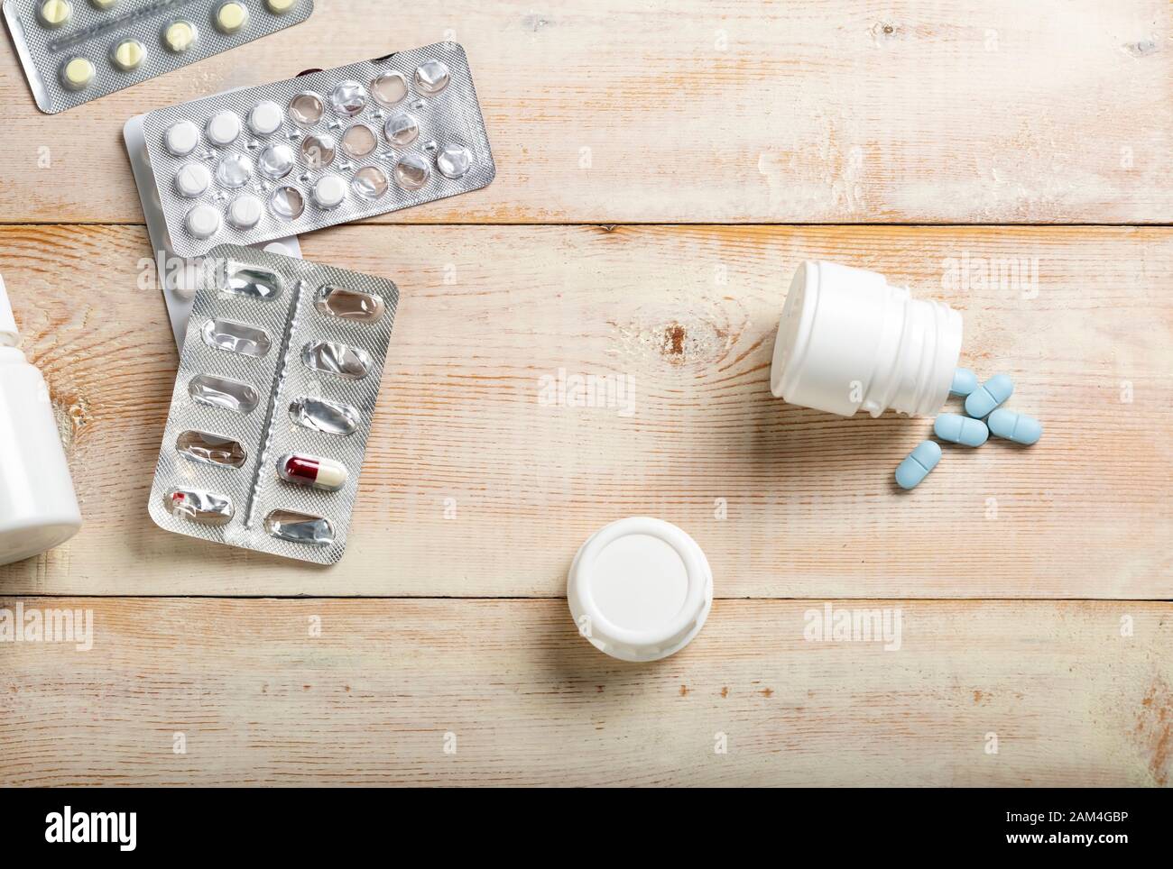 Blue pills spilled from a white plastic bottle. Different drug boxes ...