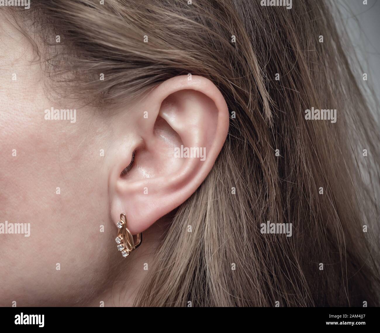 Female ear with a golden earring Stock Photo - Alamy