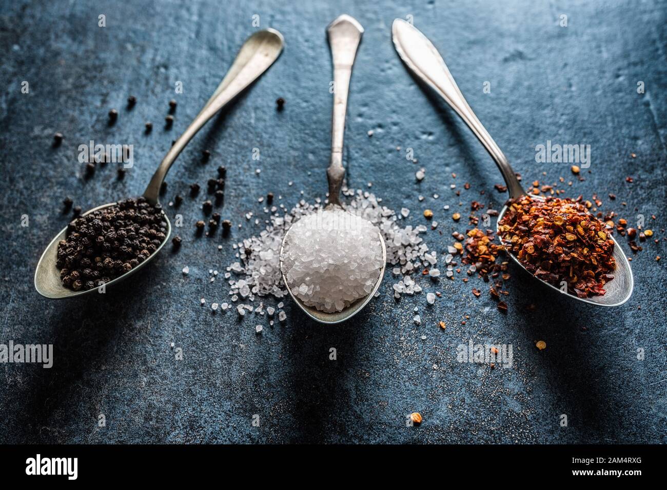 Three spoons full of salt chilli and black pepper Stock Photo - Alamy