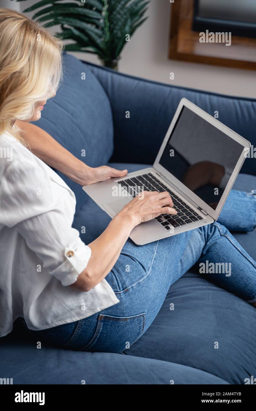 Woman on the sofa using her computer Stock Photo - Alamy