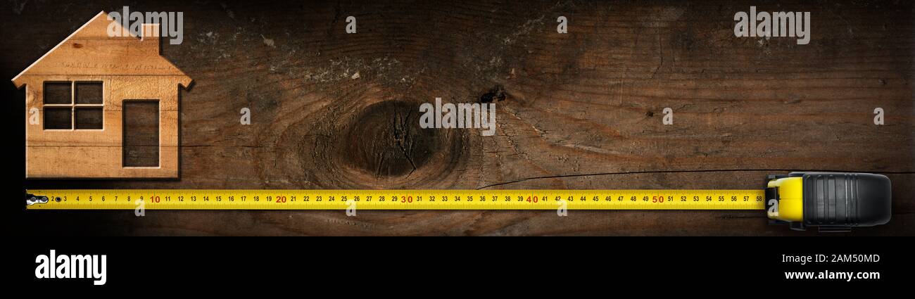 Model house and yellow tape measure on a wooden table with copy space ...