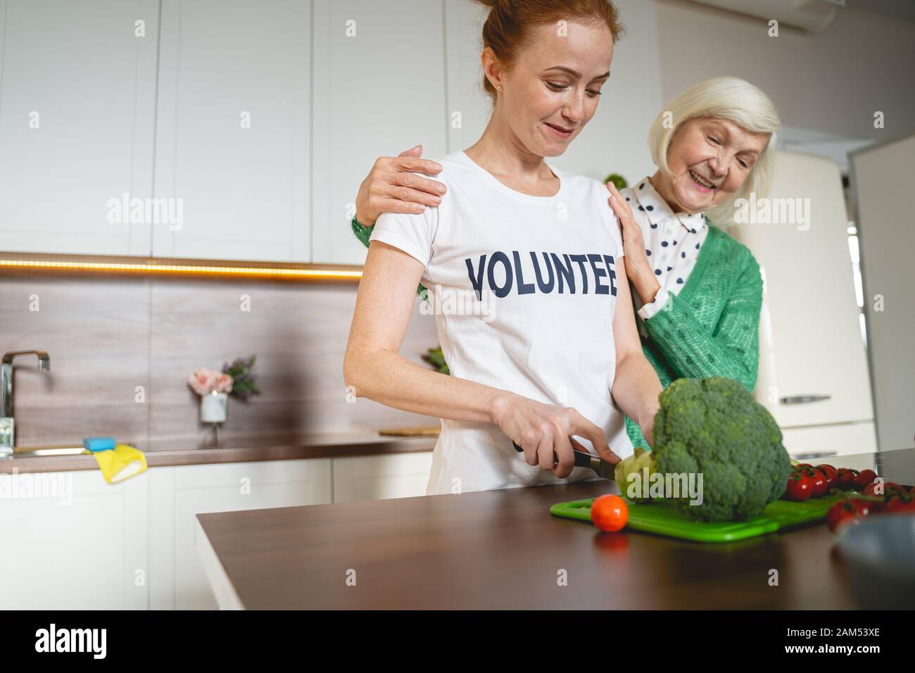 Positive delighted social worker cooking healthy dinner Stock Photo - Alamy