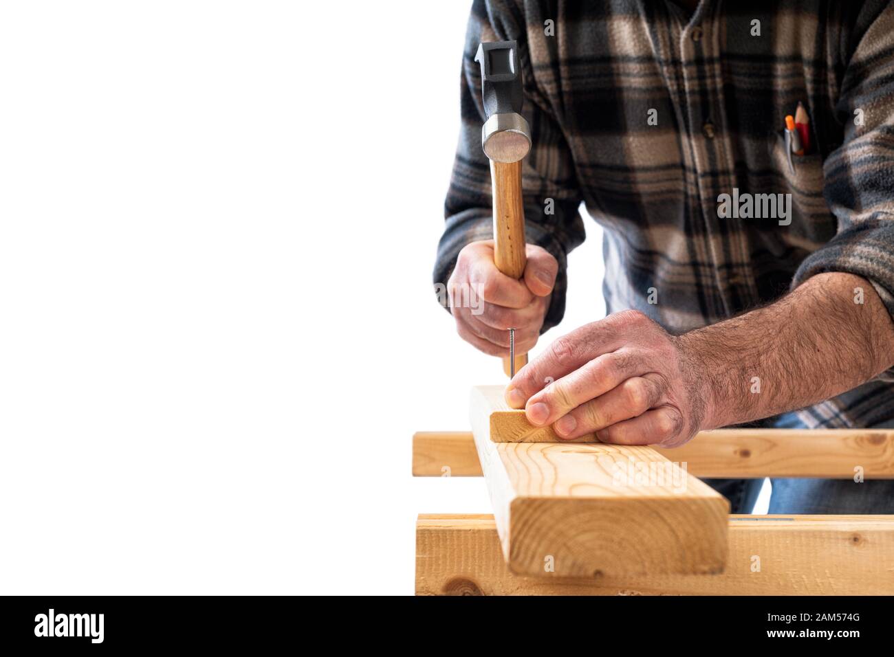 Close-up. Carpenter with hammer and nails fixes a wooden board ...