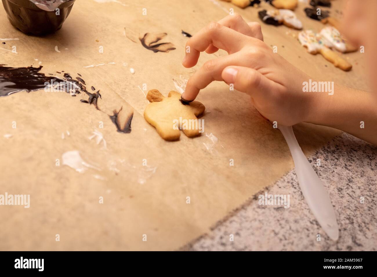 child decorates biscuits with coloured sprinkles and chocolate Stock ...