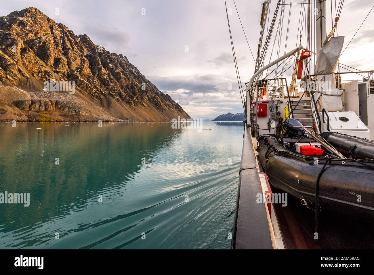 sailing ship on blue ocean along a bright brown rock massive Stock ...