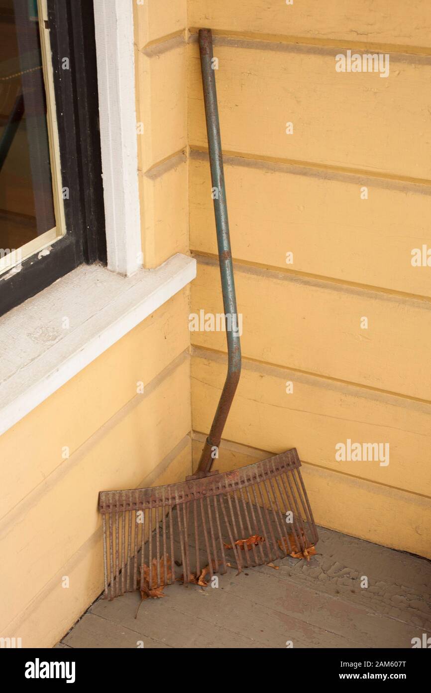 A rusty old rake leans against a wall Stock Photo - Alamy