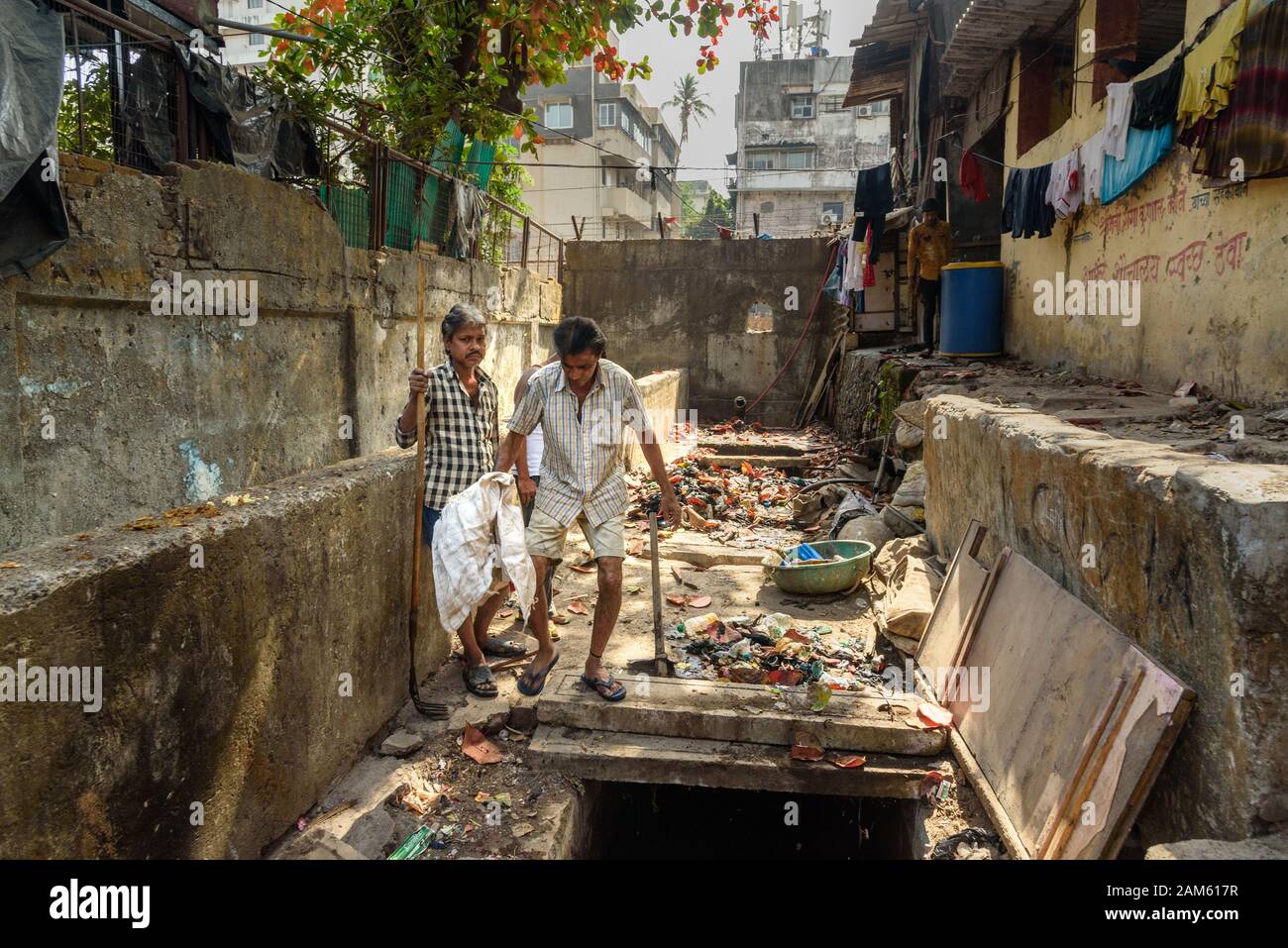Indian men cleaning gutter in Dharavi Slum at Mumbai. India Stock Photo ...