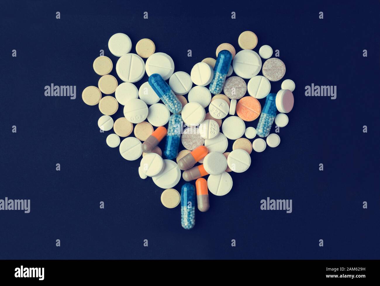 Heap of colorful pills in the shape of a heart, tablets and capsules ...