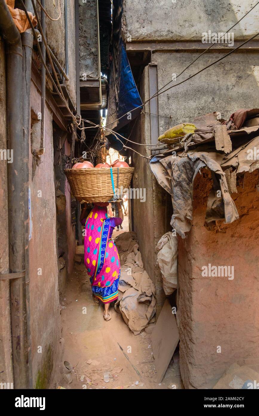 Indian woman carries basket with clay pots on her head on the street in ...