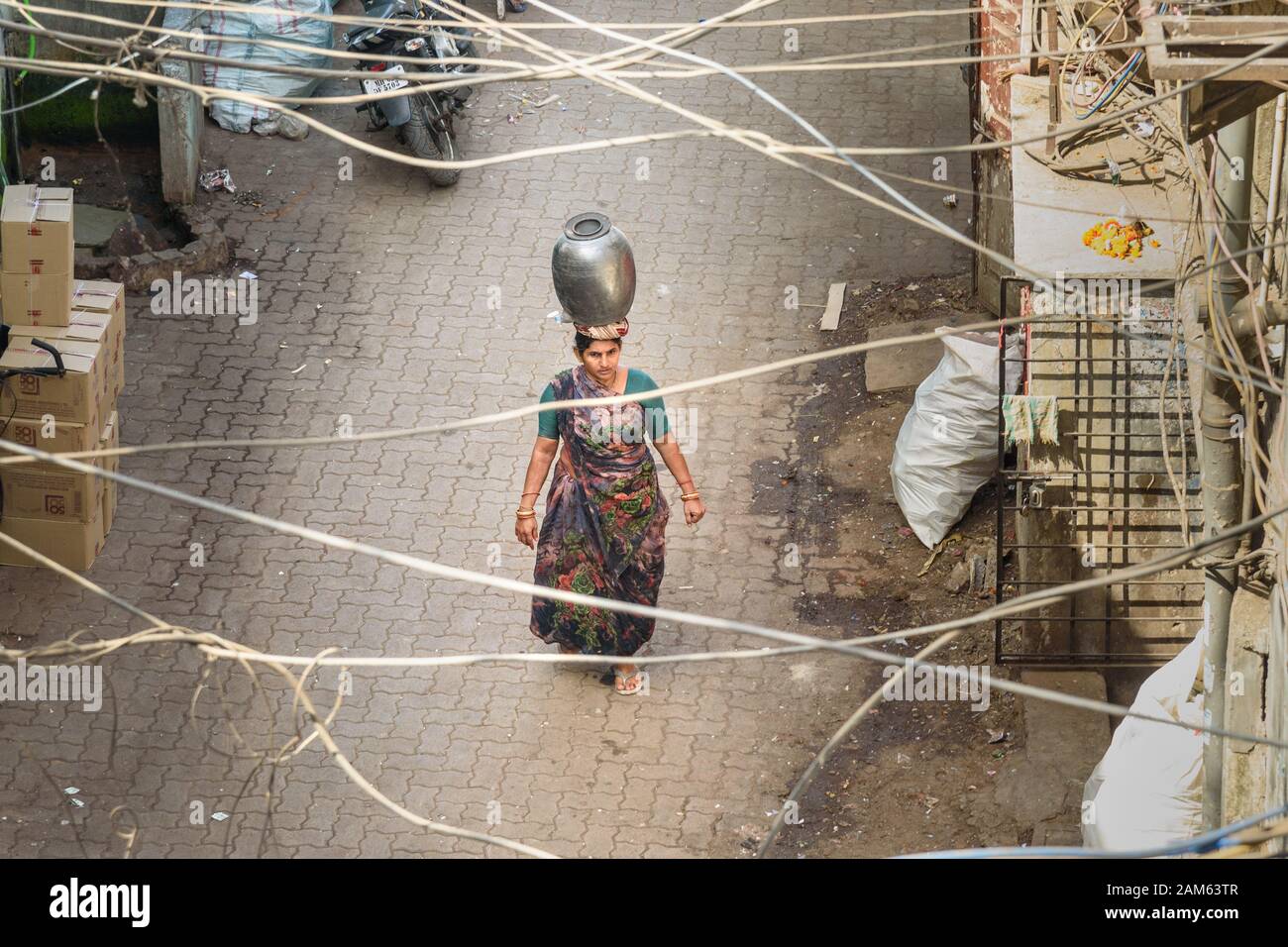 Indian woman with pot on her head on the street in Dharavi Slum at ...