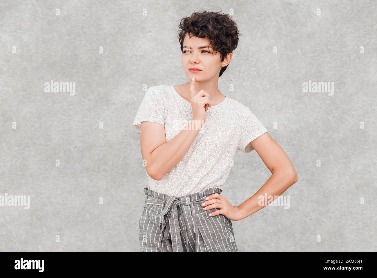 Charming young woman with creative hairstyle is posing with intrigued ...