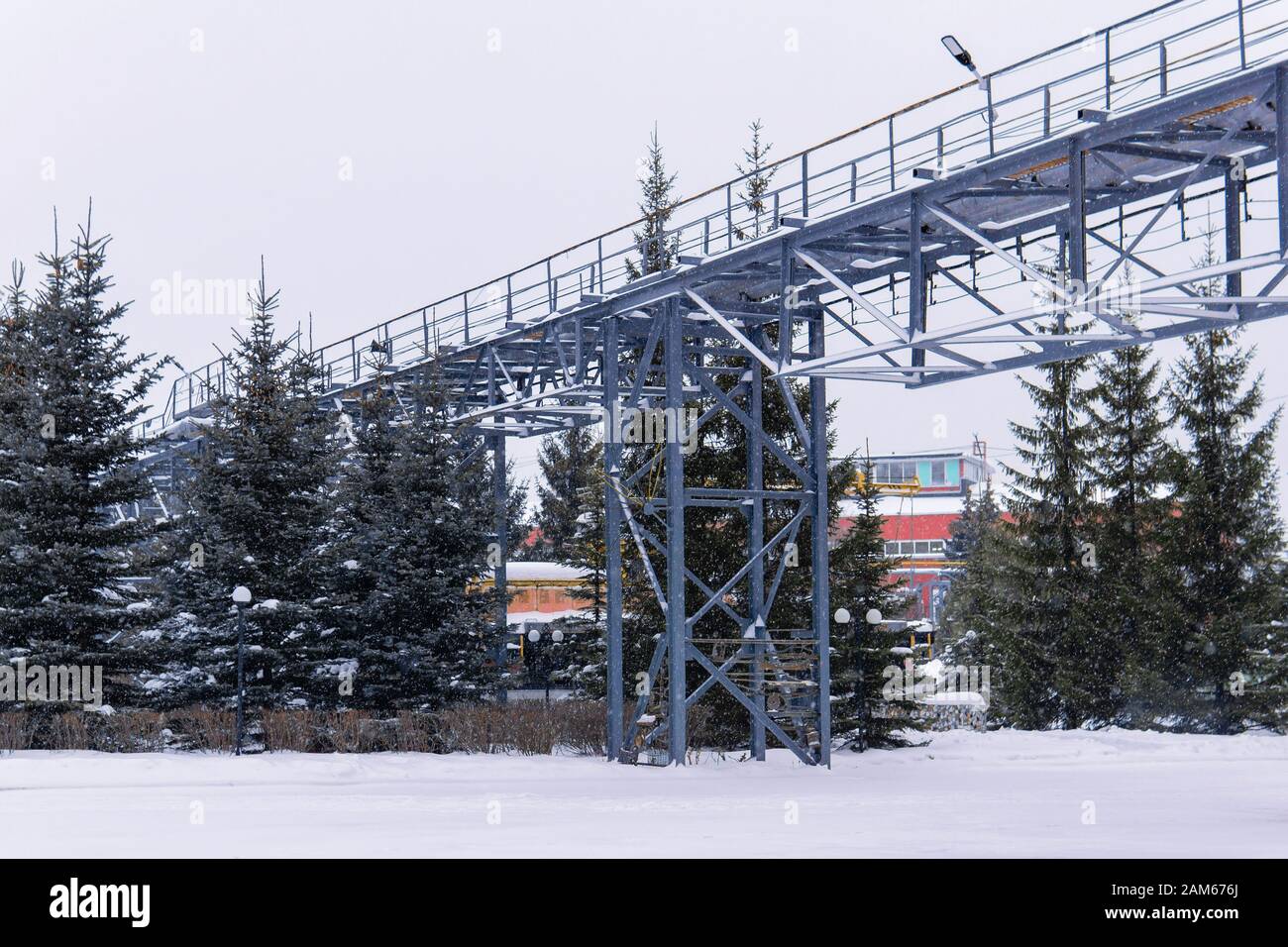 winter industrial landscape with elevated pipelines during snowfall ...
